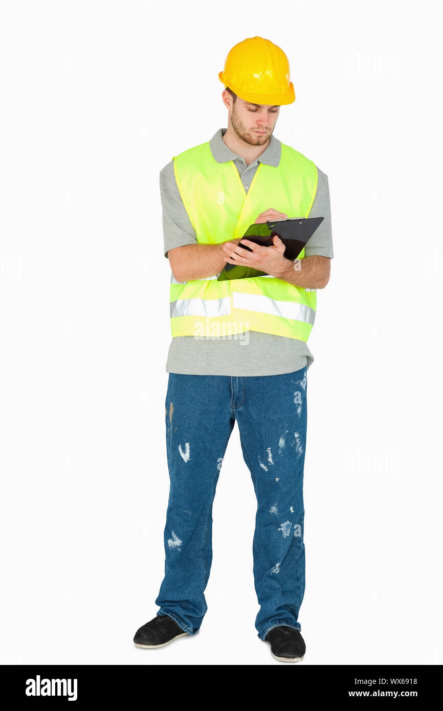 Young construction worker taking notes on his clipboard against a white ...