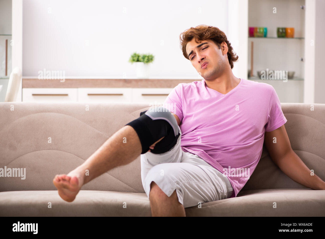 Young man with injured knee recovering at home Stock Photo - Alamy