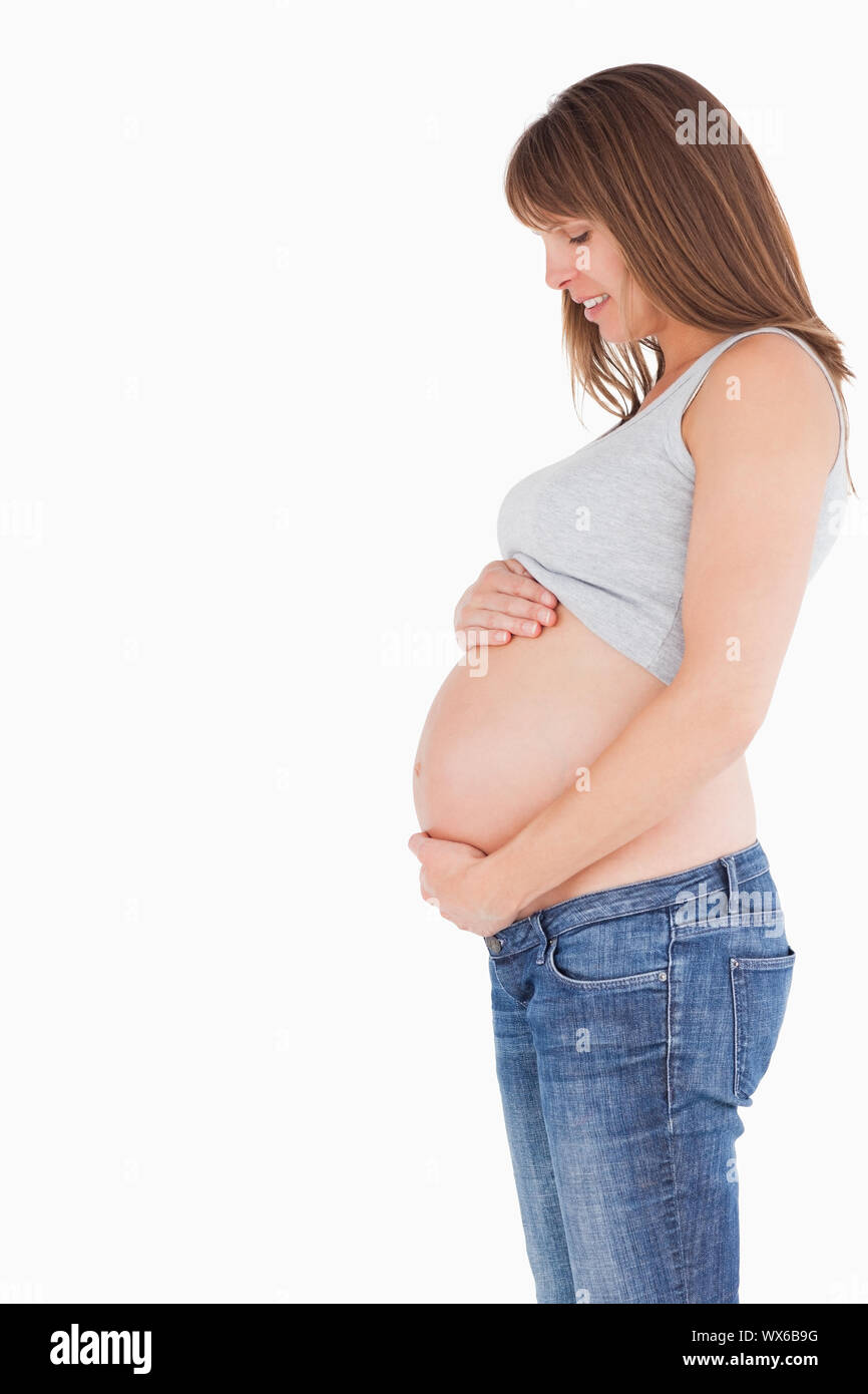 Side view of an attractive pregnant woman caressing her belly while ...