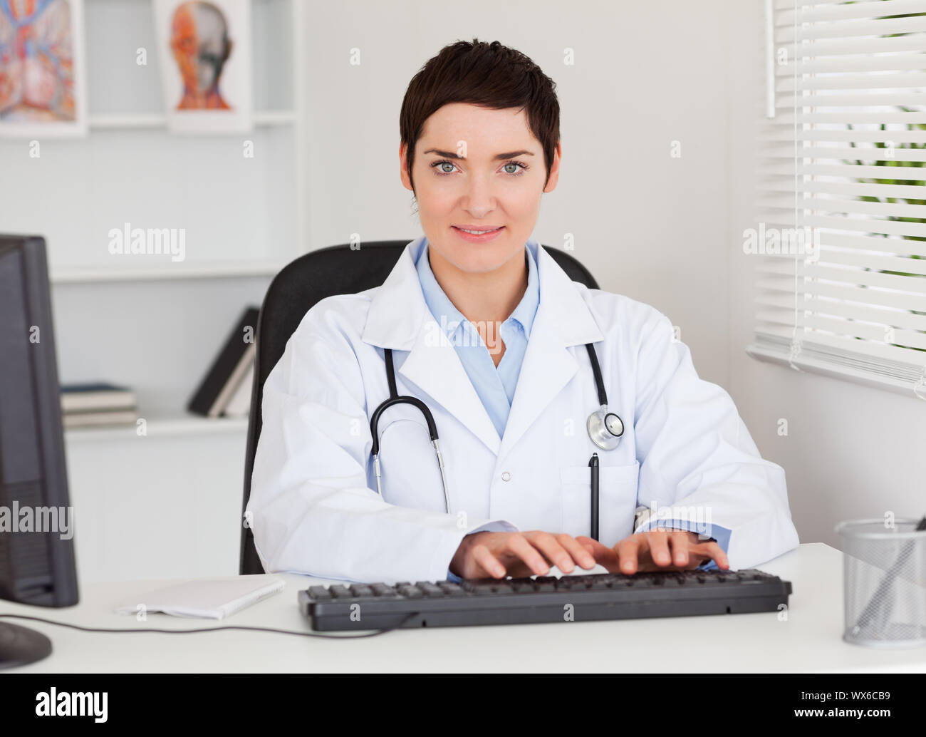 Female doctor typing with her computer in her office Stock Photo - Alamy