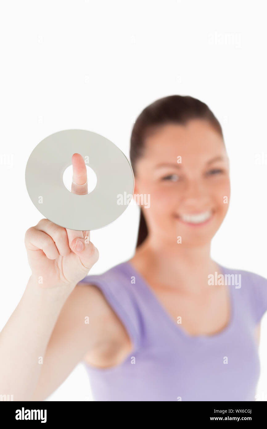 Charming woman holding a CD while standing against a white background ...