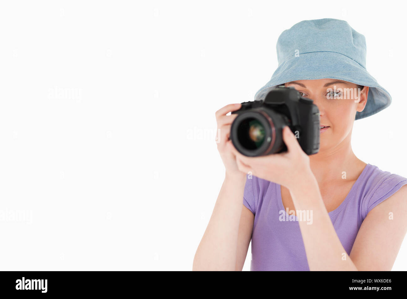 Lovely female using a camera while standing against a white background ...