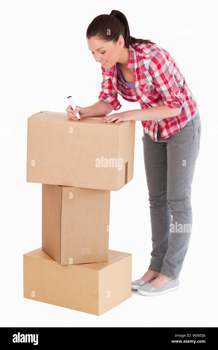 Gorgeous woman writing on cardboard boxes with a marker while standing ...