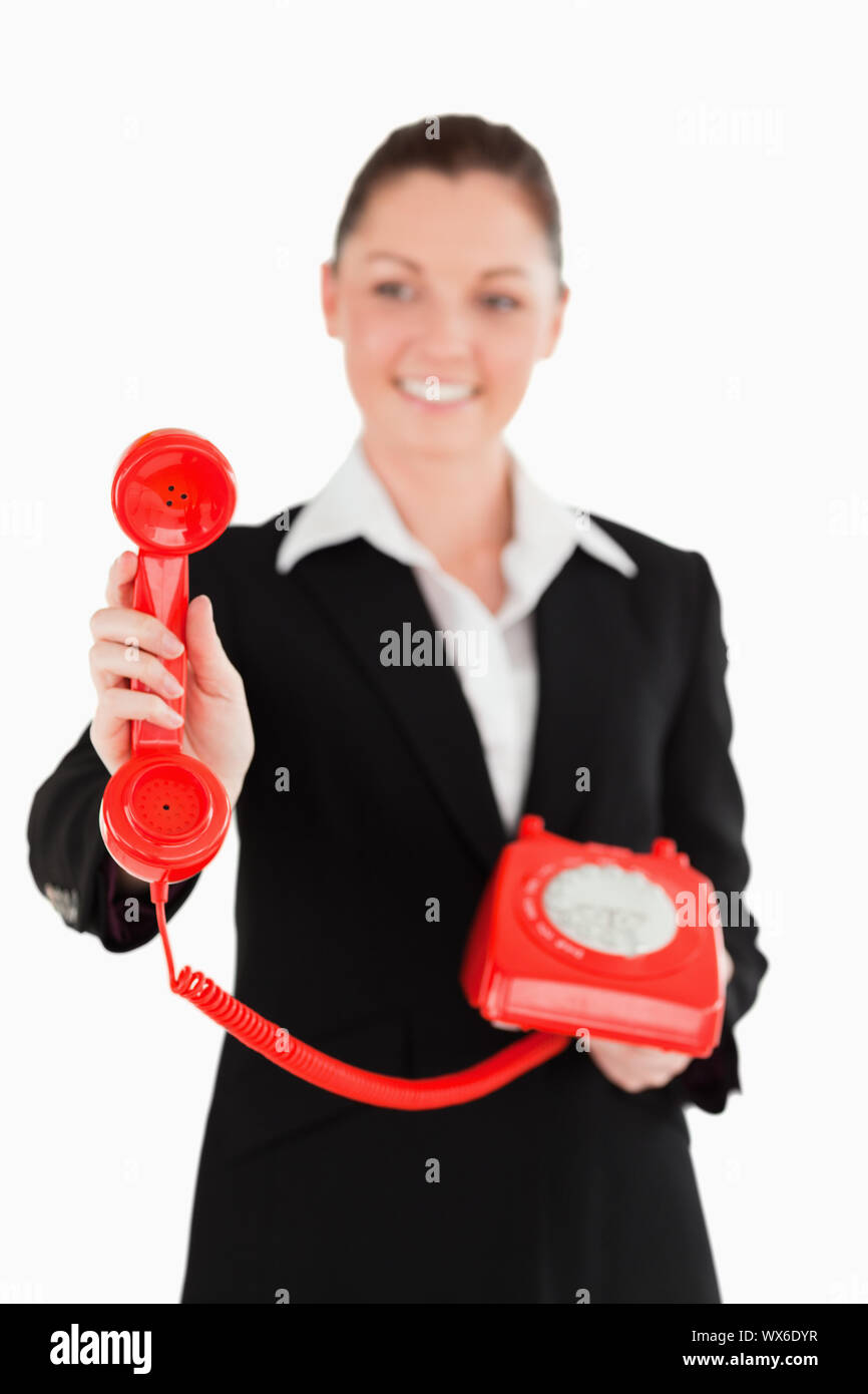 Attractive woman in suit holding a red telephone while standing against ...