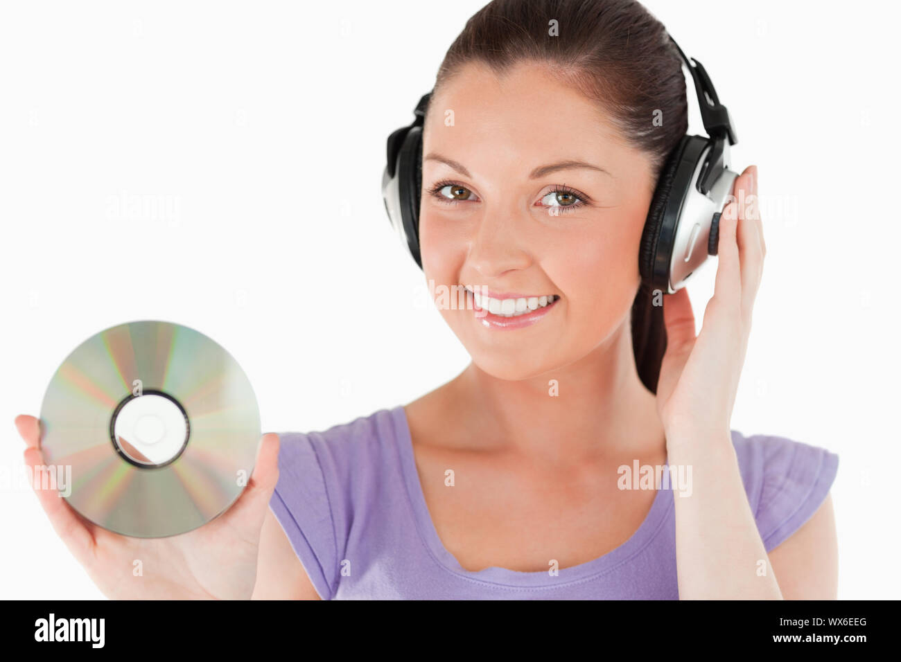 Attractive woman with headphones holding a CD while standing against a ...