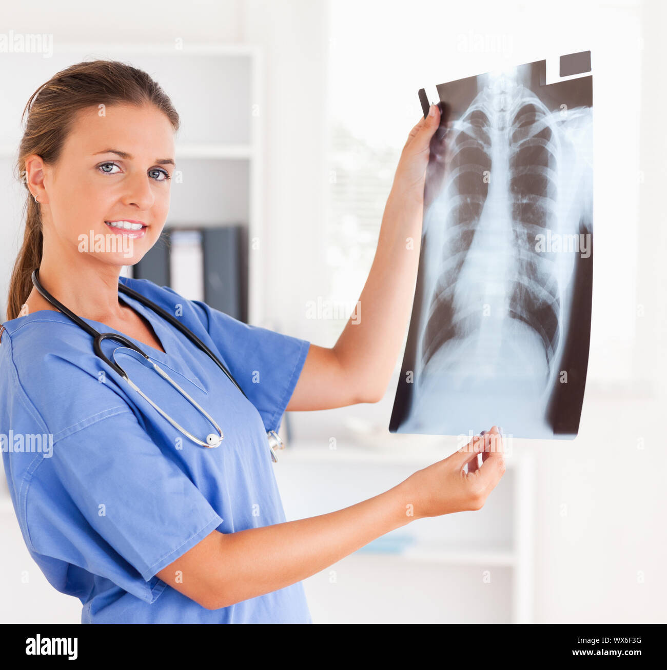 Gorgeous doctor with stethoscope and x-ray looking into camera in the ...