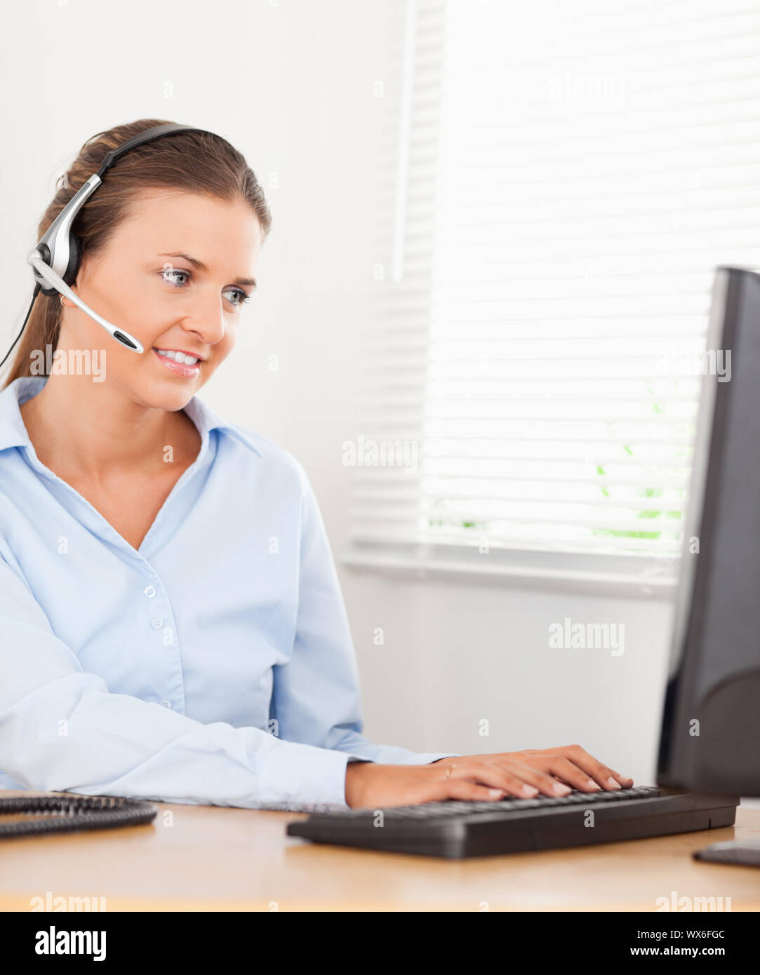 An operator with headset is sitting in an office while typing on a ...