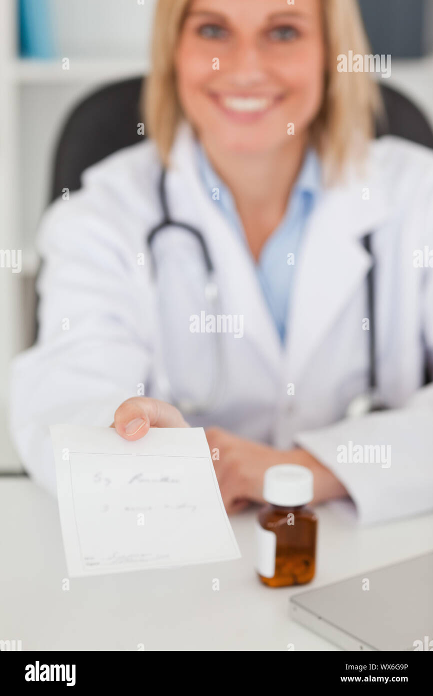 Smiling doctor giving prescription looks into camera in her office ...