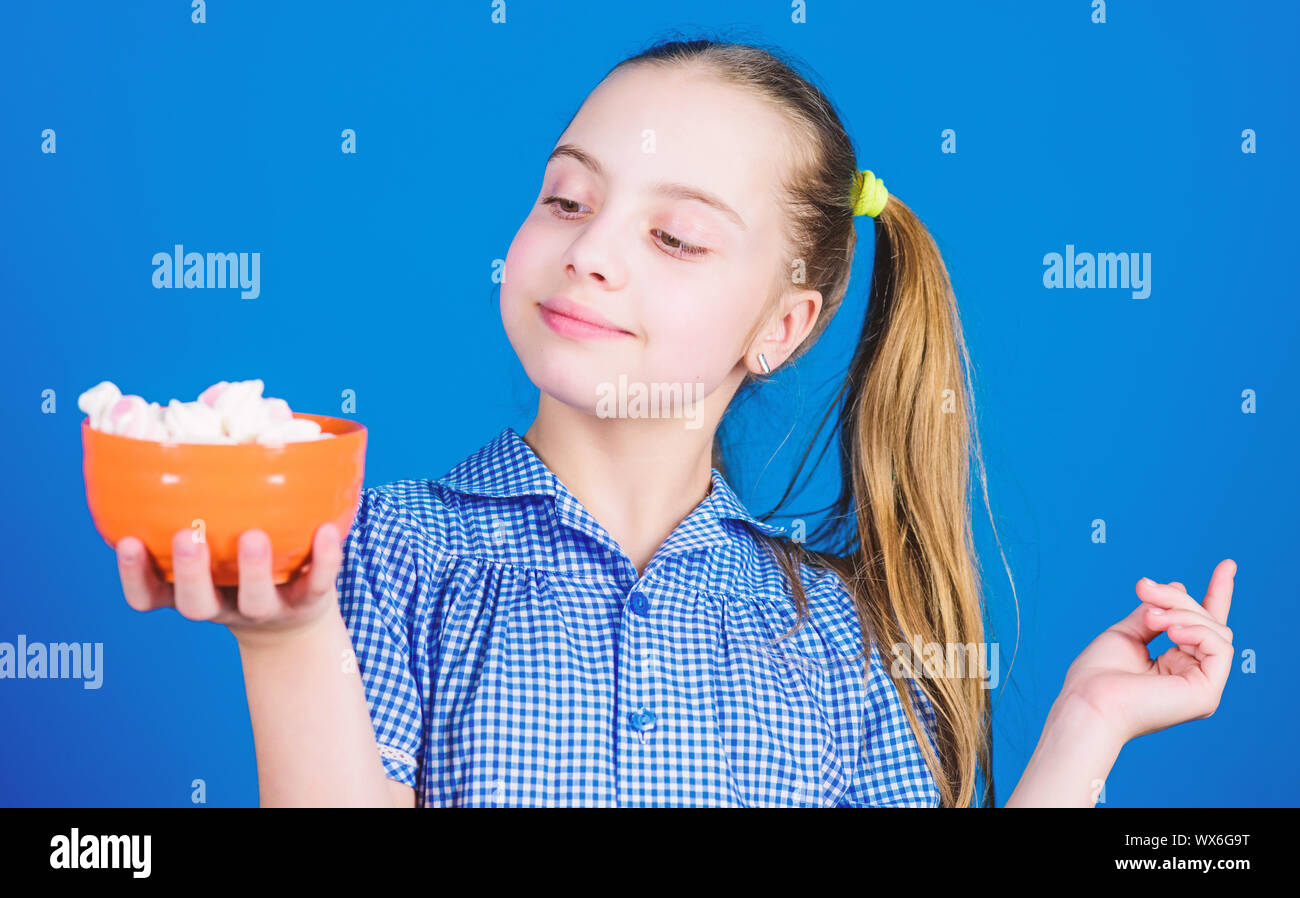 Girl smiling face hold bowl sweets marshmallows in hand blue background ...