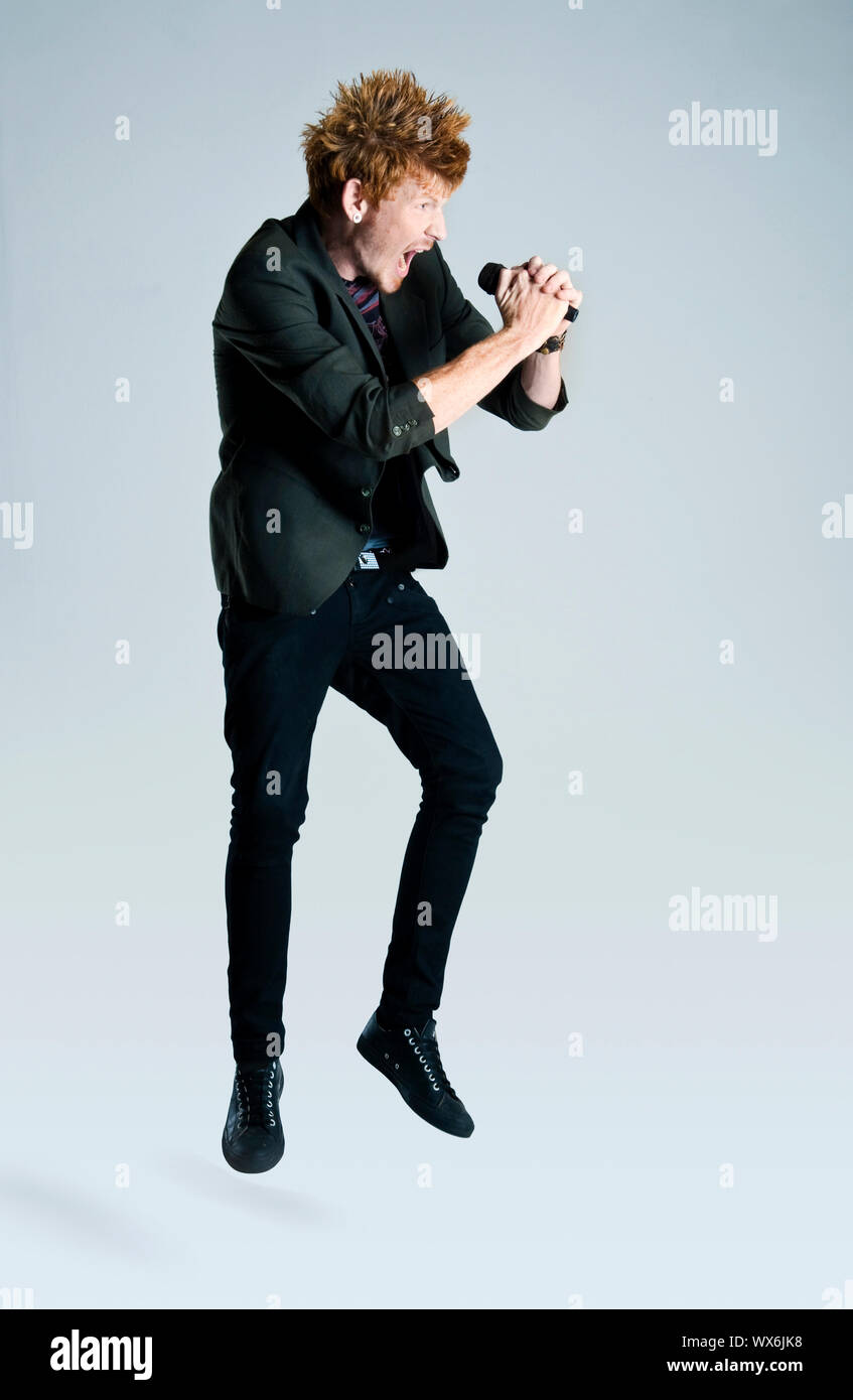 Rock star jumps and sings into the mic Stock Photo - Alamy