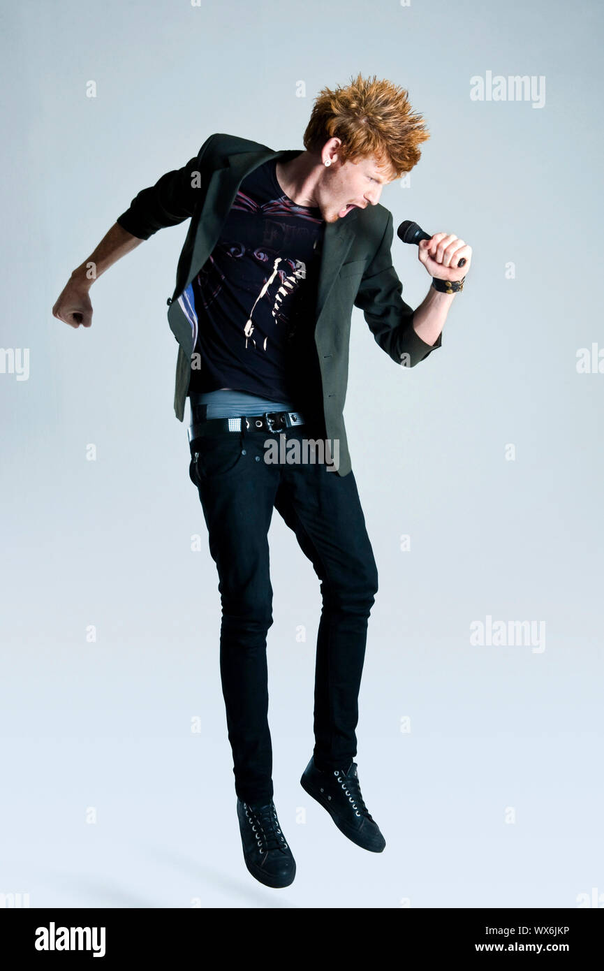 Rock star jumps and sings into the mic Stock Photo - Alamy