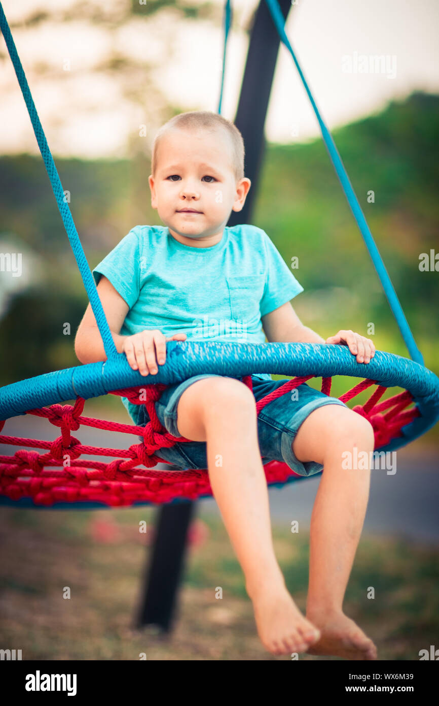 Little boy swinging on a swing Stock Photo - Alamy