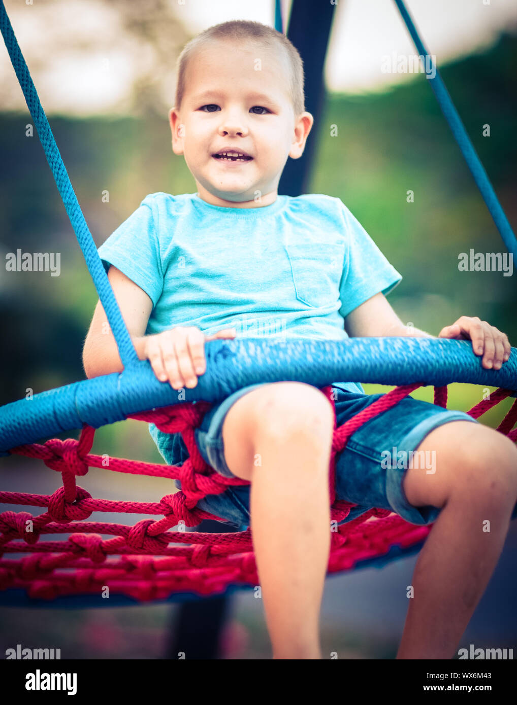 Little boy swinging on a swing Stock Photo - Alamy