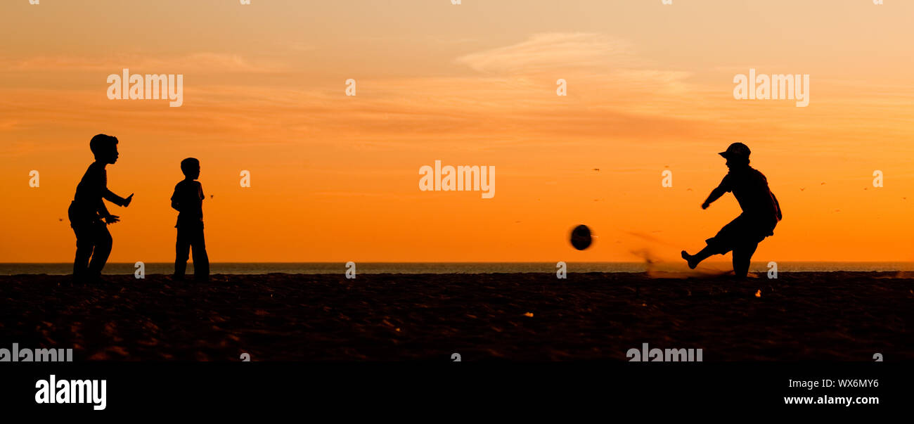 Kids having fun on the beach playing football Stock Photo - Alamy