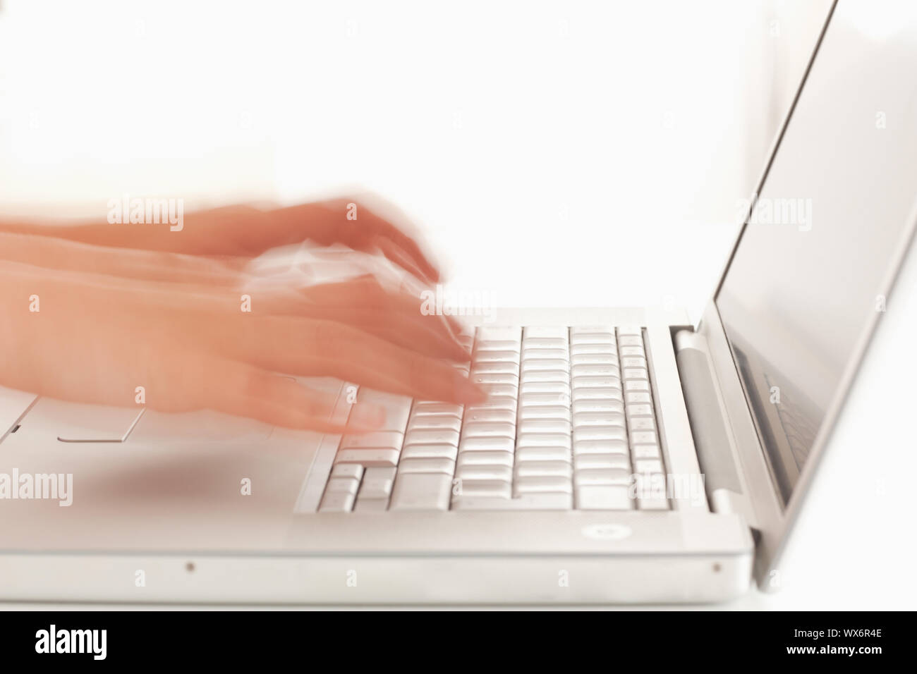 Slightly blurred hands heading to keyboard of laptop Stock Photo - Alamy