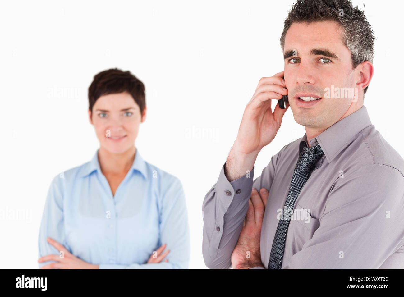 Businessman making a phone call while his colleague is posing against a ...