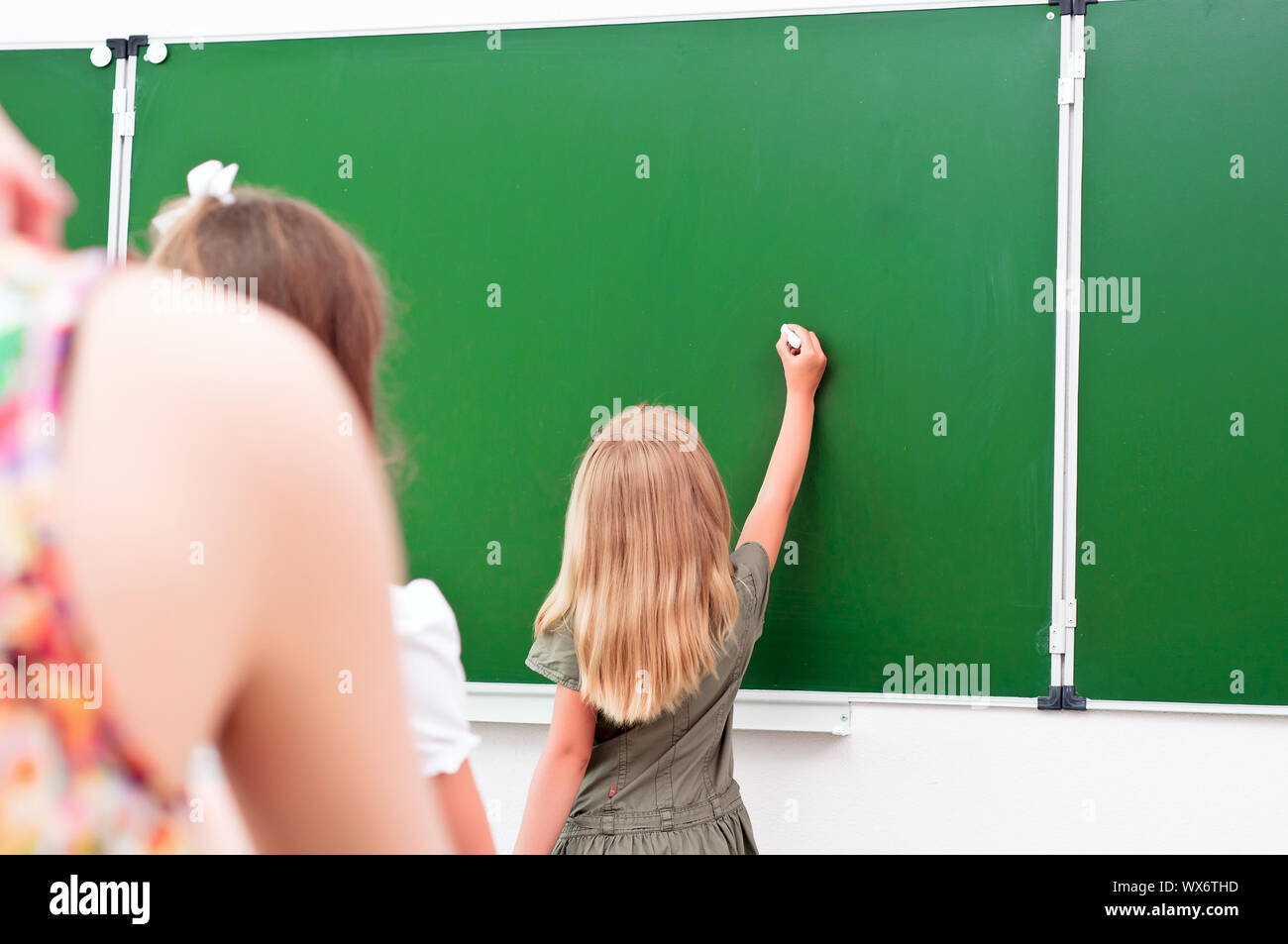school girl writes on the blackboard in class sitting other students ...