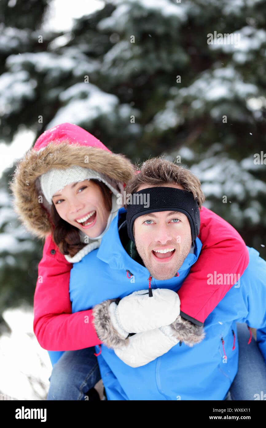 Young excited happy winter couple doing piggyback having fun outside in ...