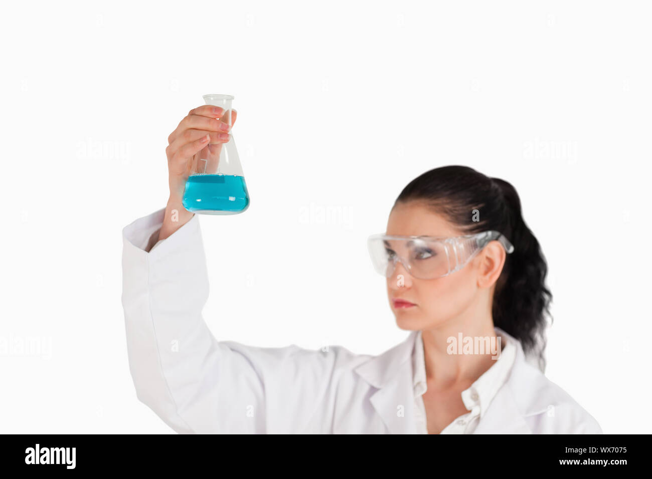 Dark-haired scientist conducting an experiment while looking at a blue ...