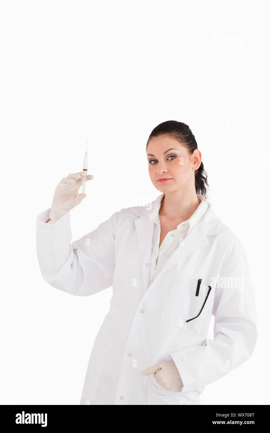 Doctor looking at the camera while holding a syringe on a white ...