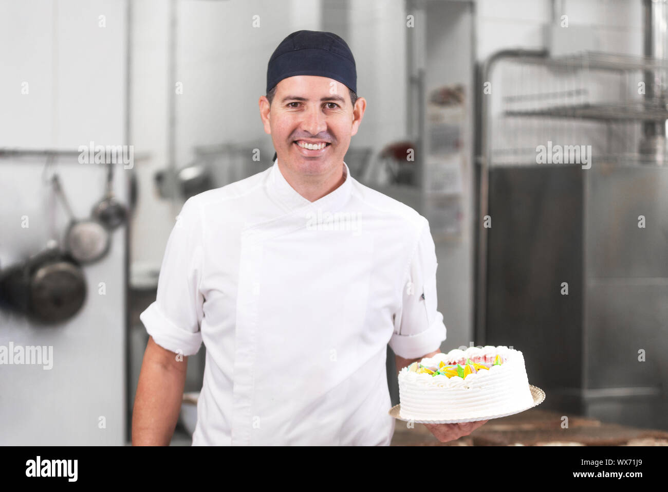 Smiling pastry Chef showing a cake Stock Photo - Alamy