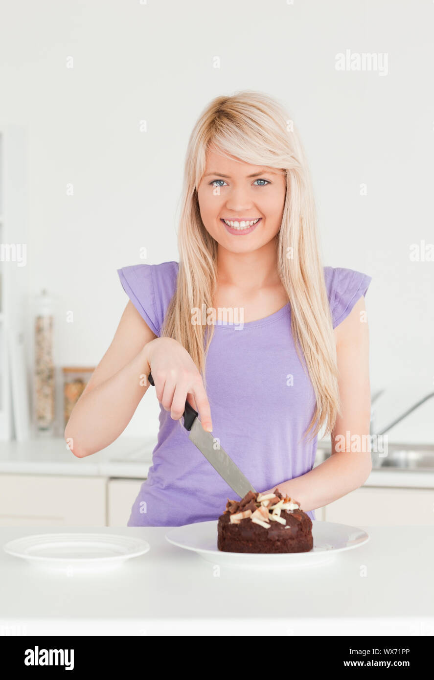 Beautiful blonde female cutting a cake in a plate in the kitchen Stock ...