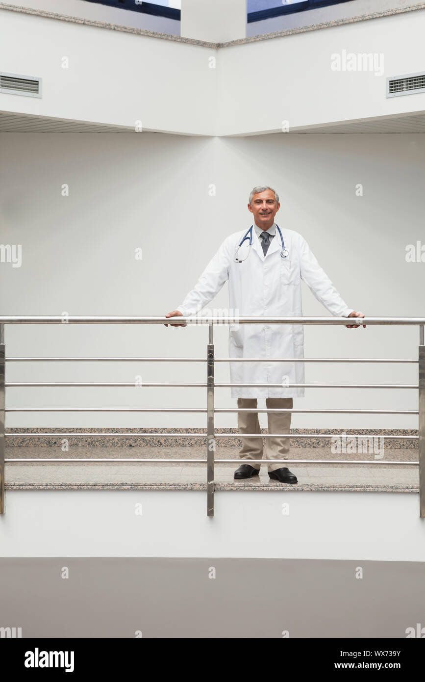 Doctor standing at the railing of the hospital corridor smiling Stock ...