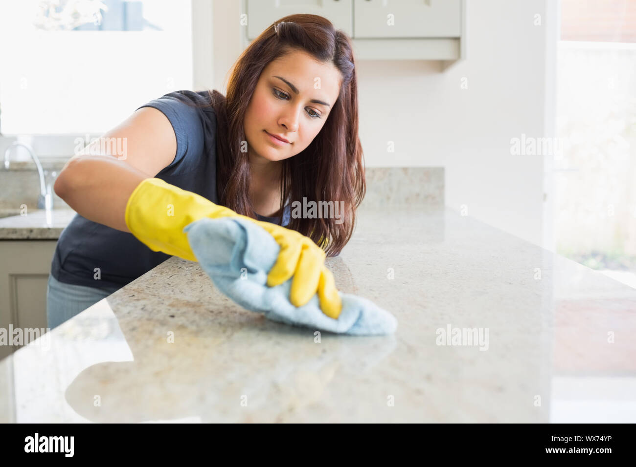 Concentrated woman scrubbing the bar in kitchen Stock Photo - Alamy