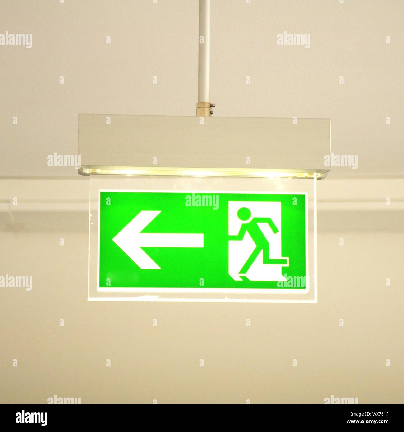 green emergency exit sign showing the way to escape Stock Photo - Alamy