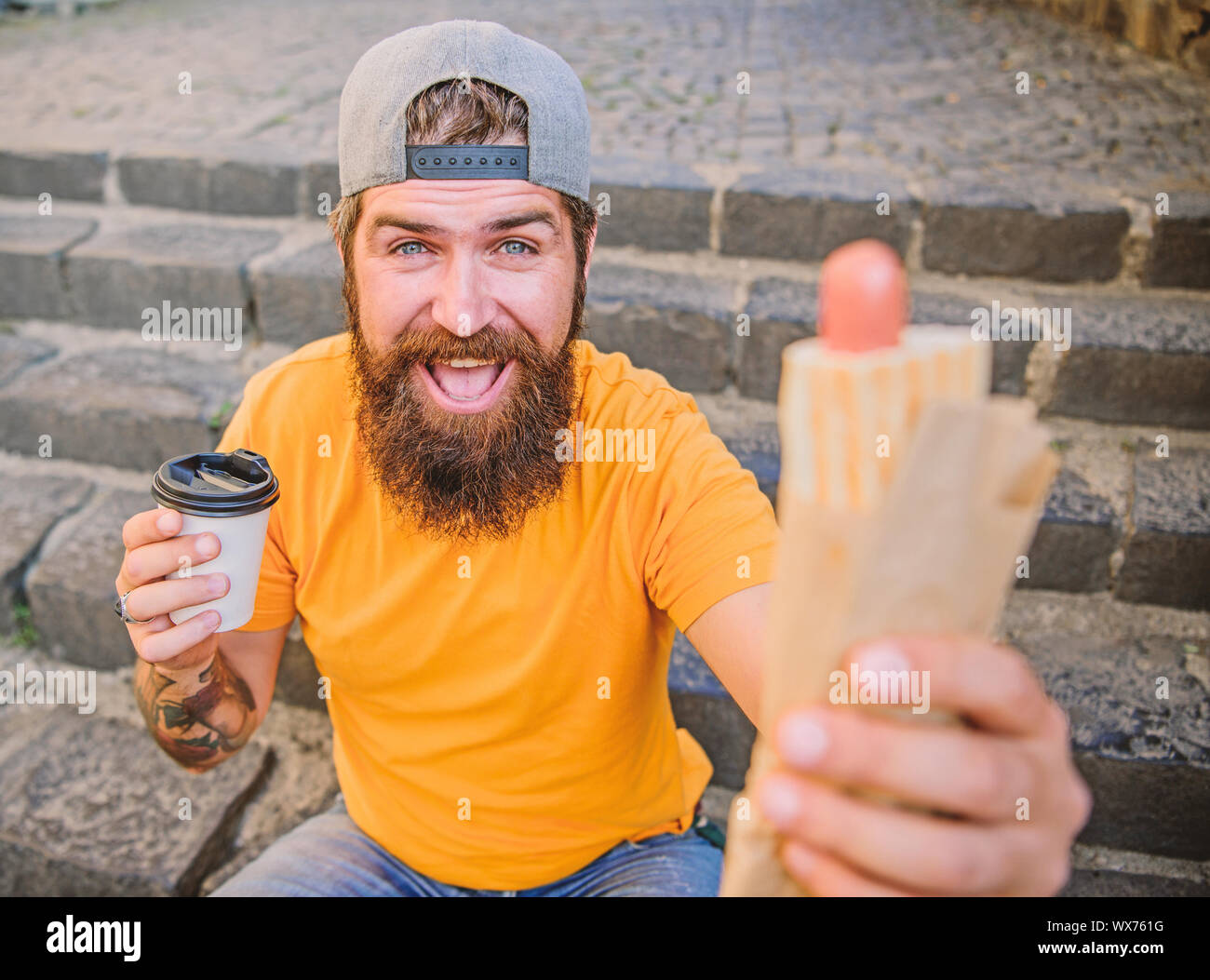 Hungry man snack. Guy eating hot dog. Man bearded bite tasty sausage ...