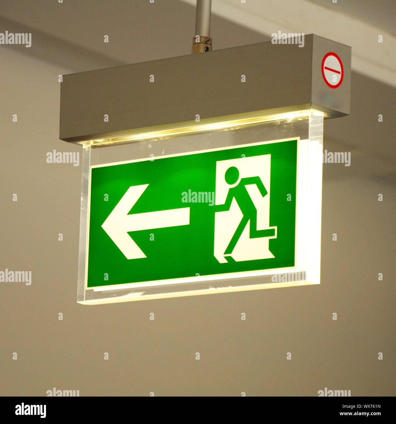 green emergency exit sign showing the way to escape Stock Photo - Alamy