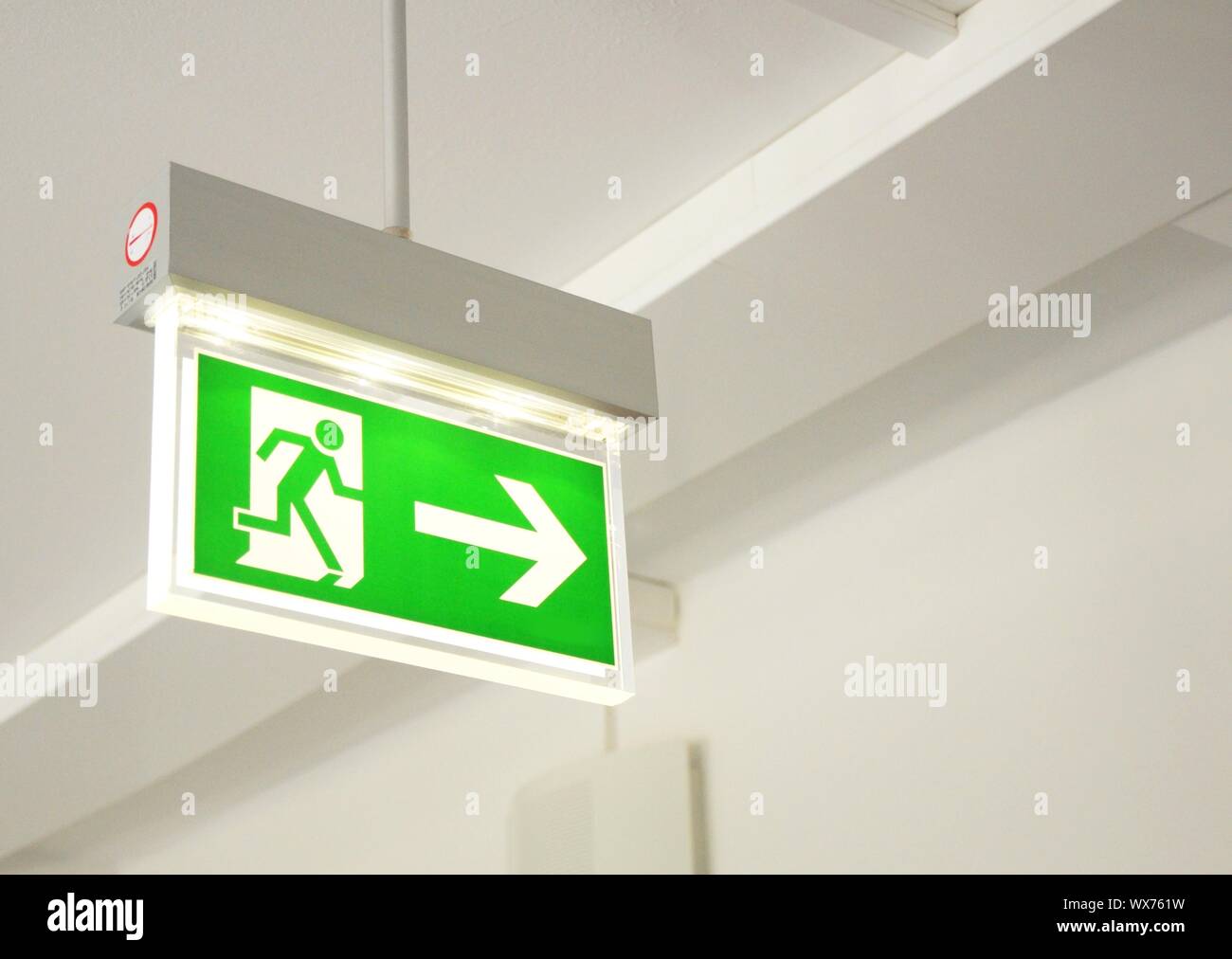 green emergency exit sign showing the way to escape Stock Photo - Alamy