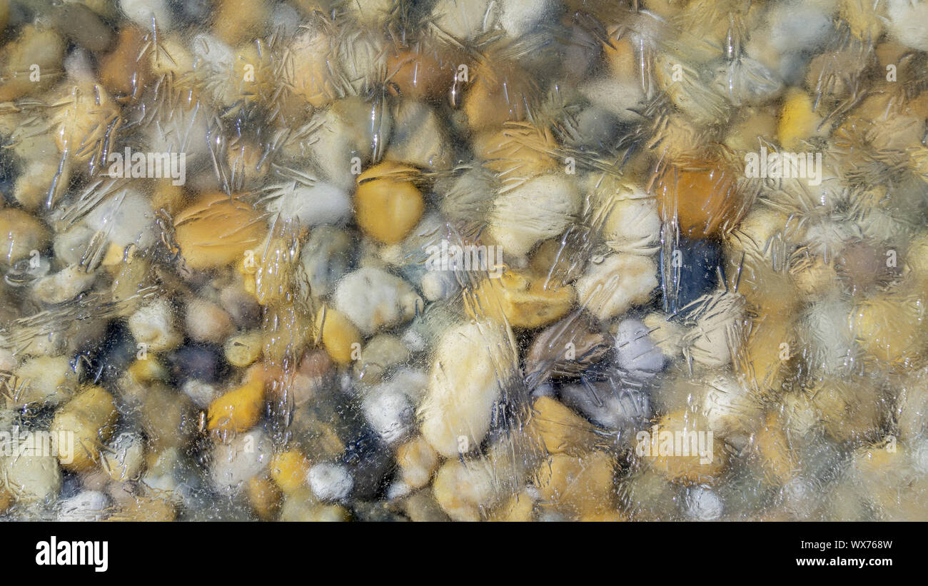 Pebbles on the beach under ice Stock Photo - Alamy