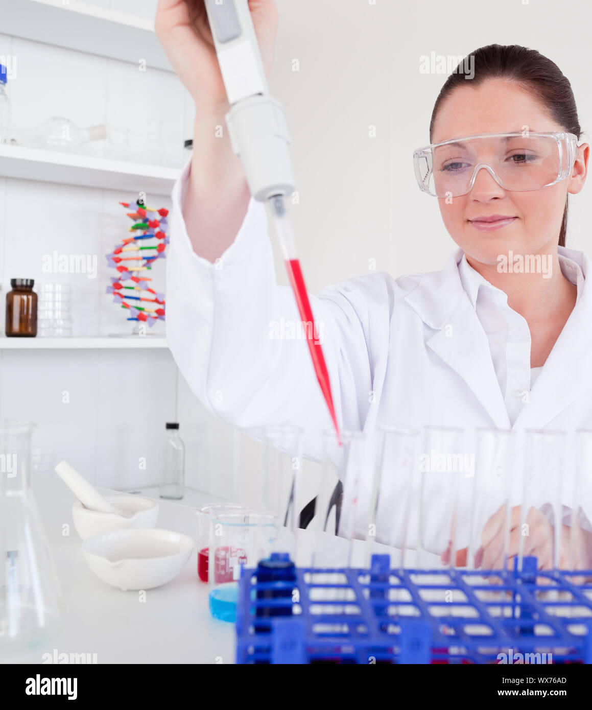 Cute female biologist holding a manual pipette with sample from test ...