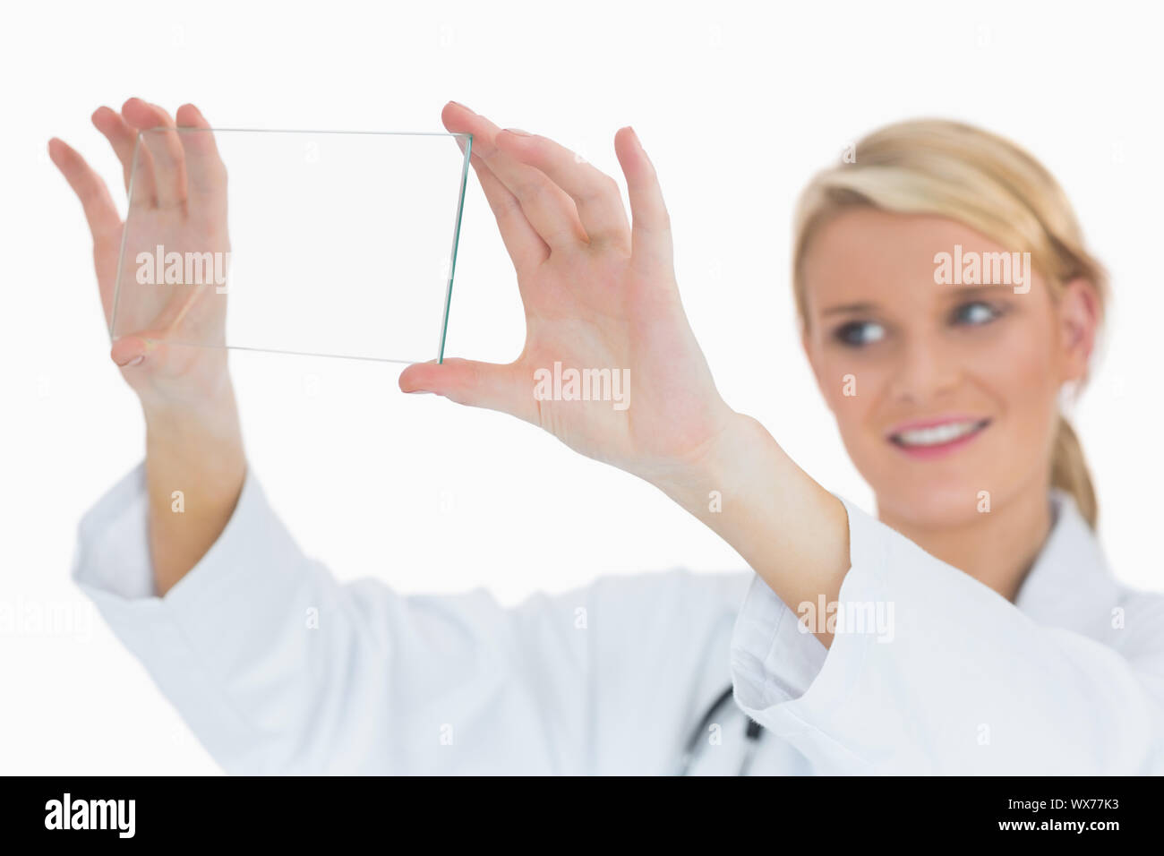 Smiling female doctor wearing a stethoscope and analysing a glass plate ...