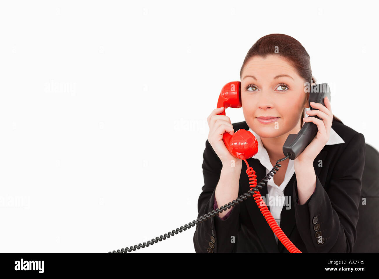 Cute secretary answering two phone calls at the same time against a ...