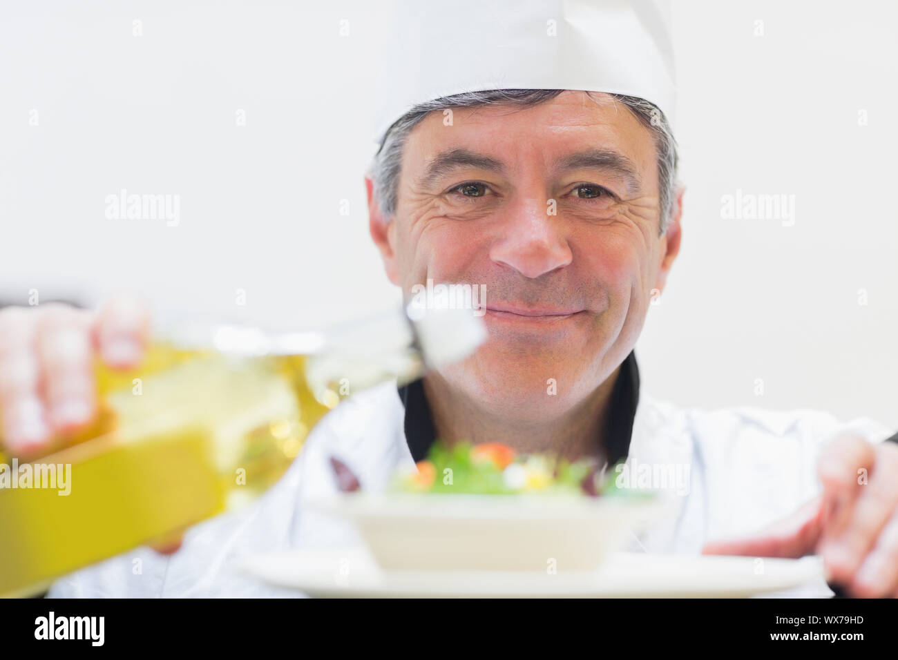 Smiling chef dressing a salad in kitchen Stock Photo - Alamy