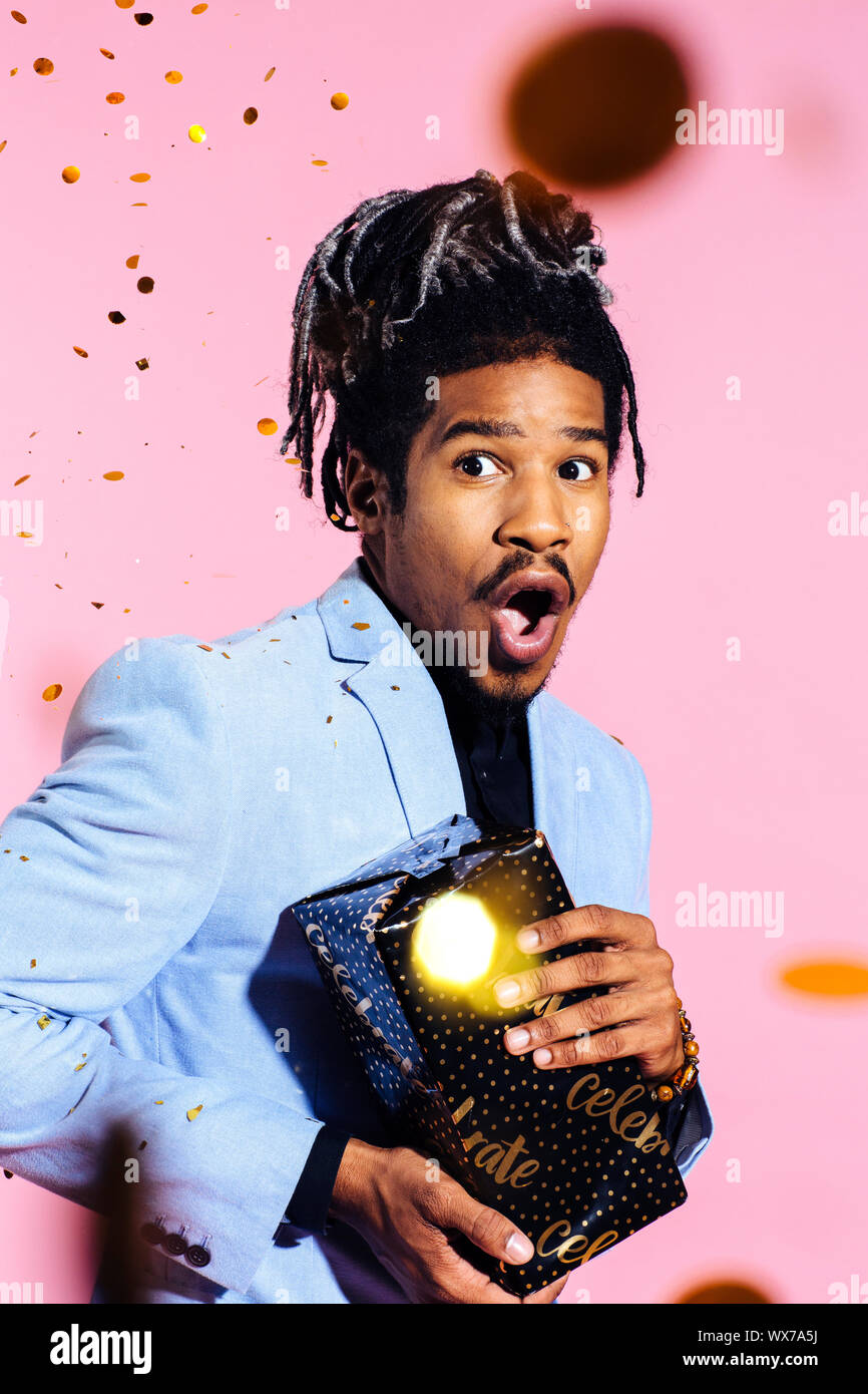 Portrait of a very excited man with gift and mouth open, against studio ...