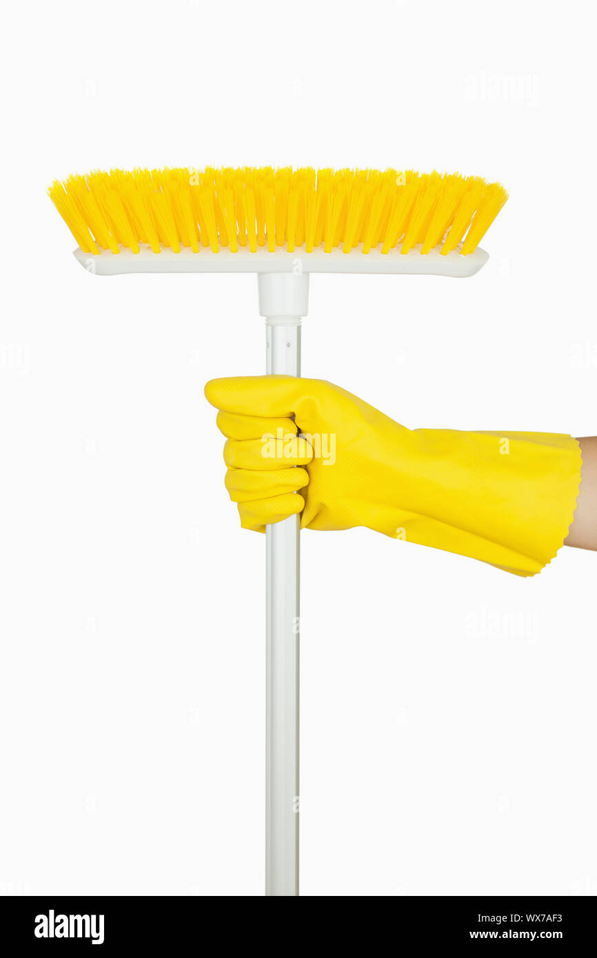 Hand in rubber glove holding broom Stock Photo - Alamy