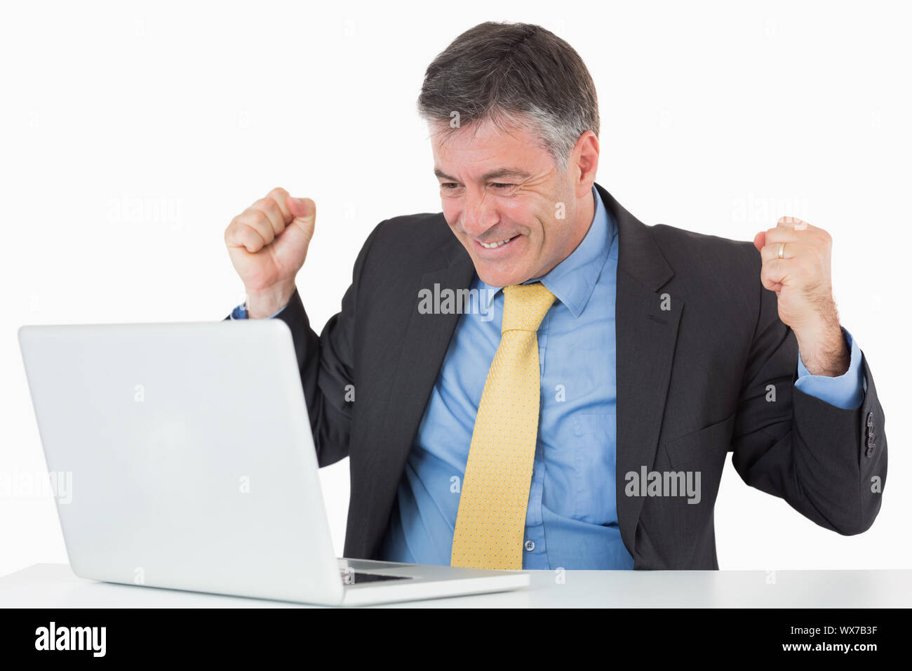 Very happy man sitting at his desk with his laptop on white background ...