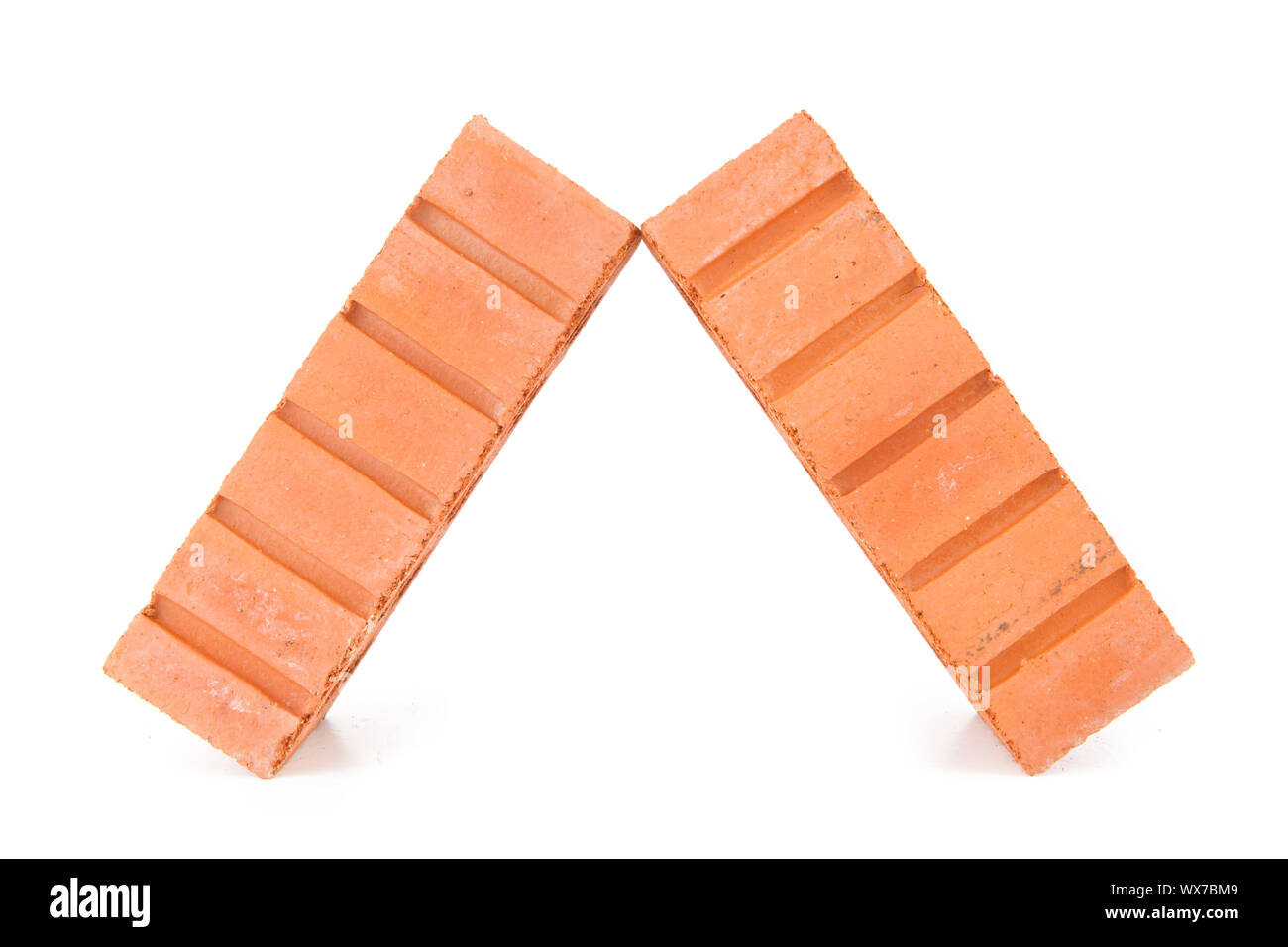 Two clay bricks leaning against each other with a white background ...