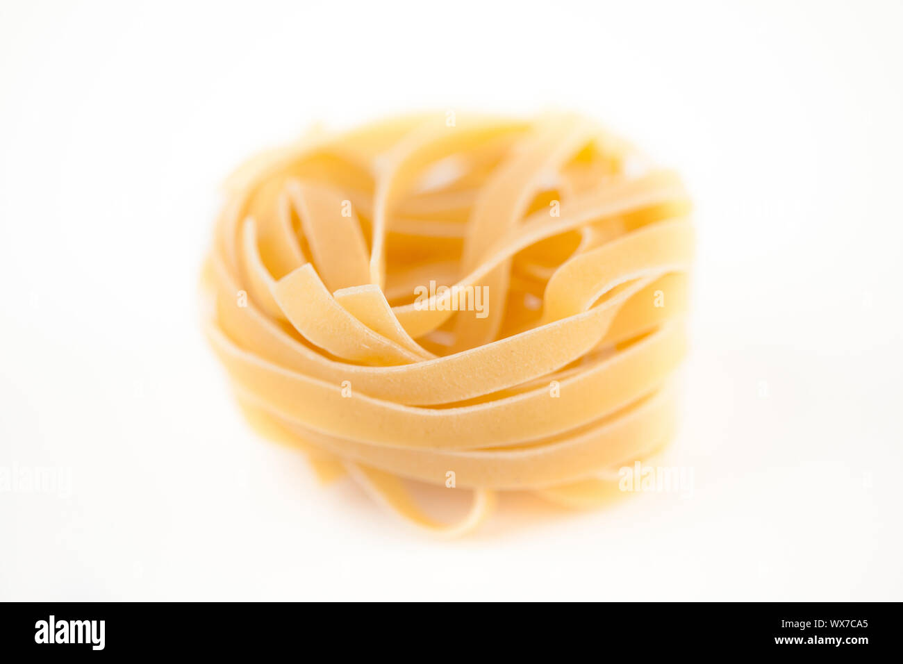 Dry tagliatelle on white background Stock Photo - Alamy