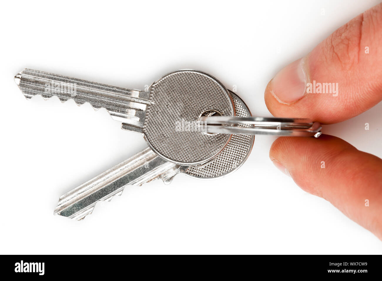 Finger holding set of keys against white background Stock Photo - Alamy