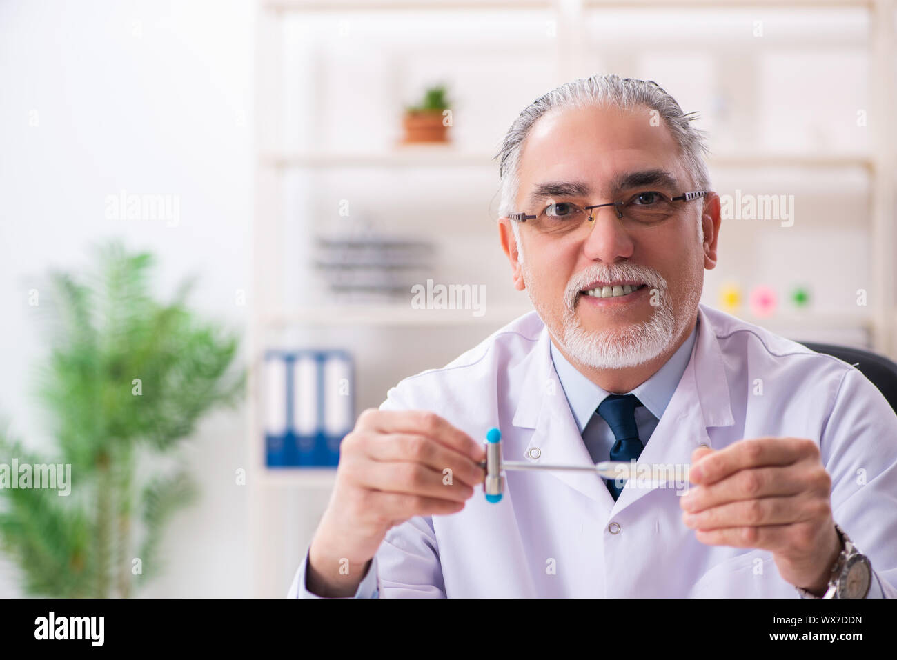 Aged male doctor with hammer Stock Photo - Alamy
