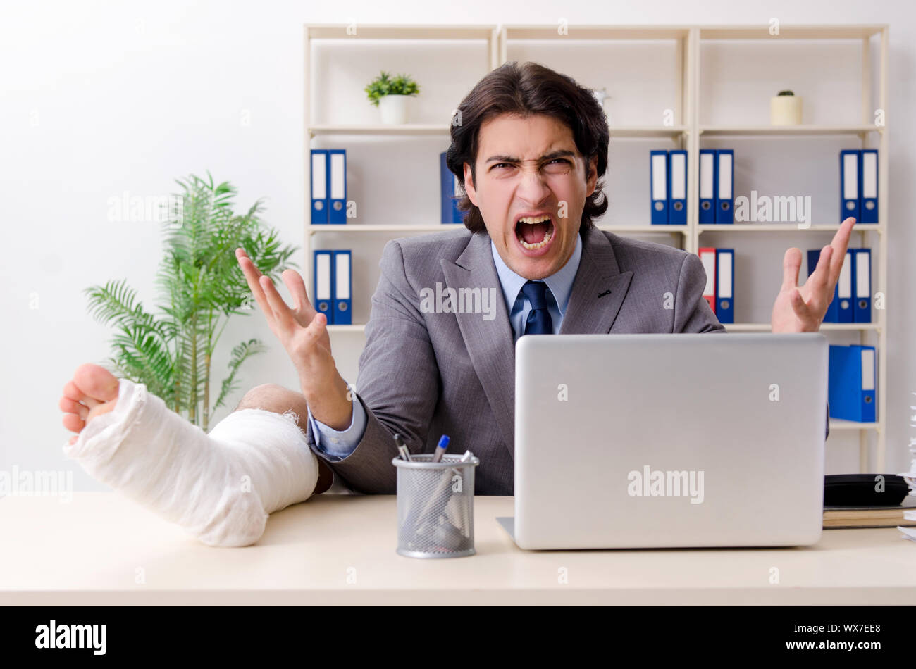 Leg injured employee working in the office Stock Photo - Alamy