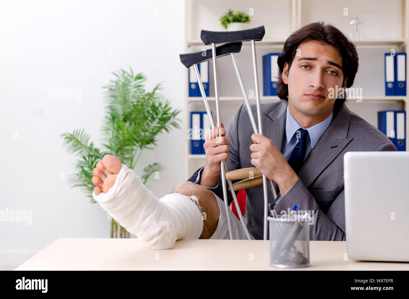 Leg injured employee working in the office Stock Photo - Alamy