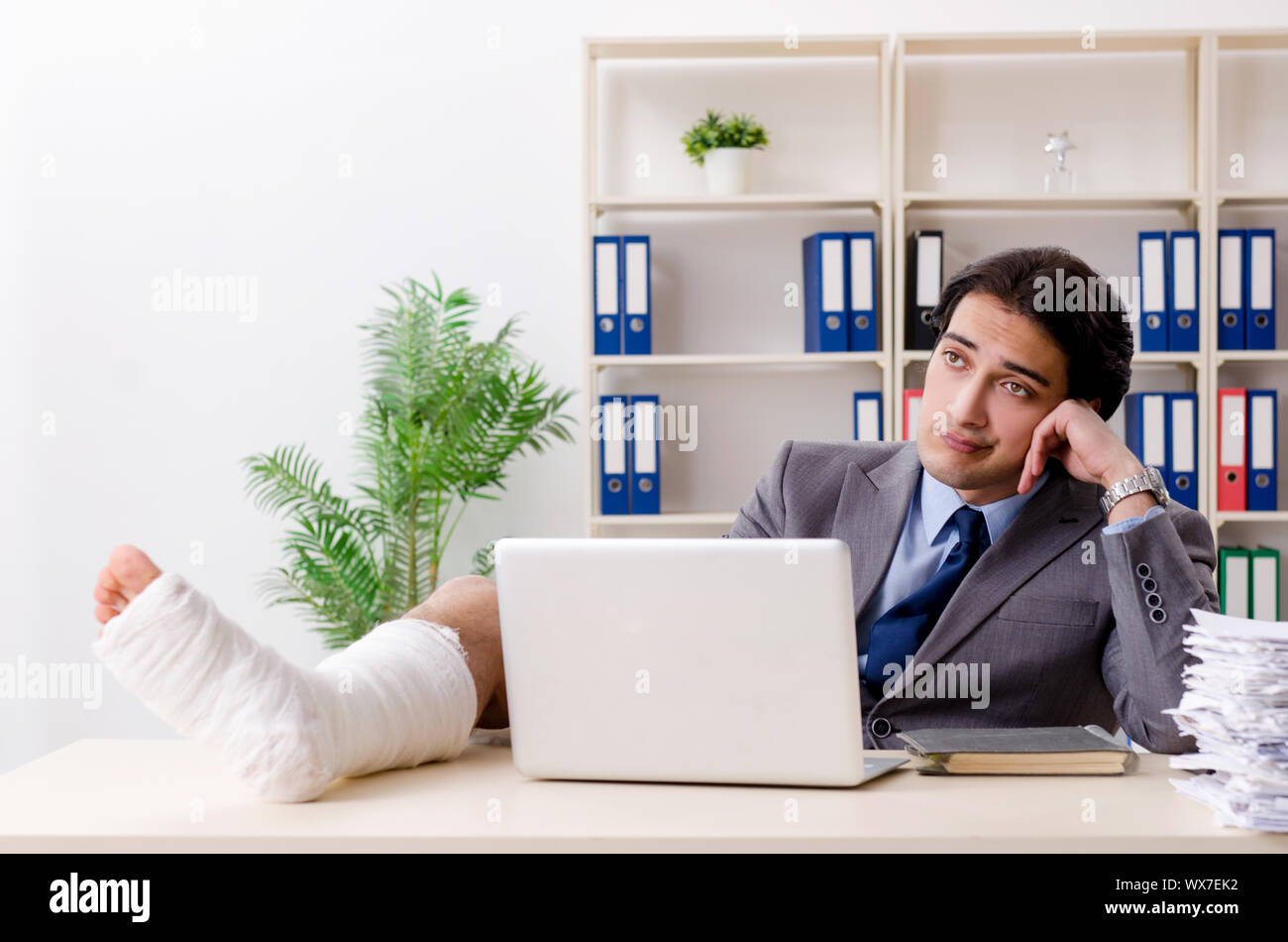 Leg injured employee working in the office Stock Photo - Alamy
