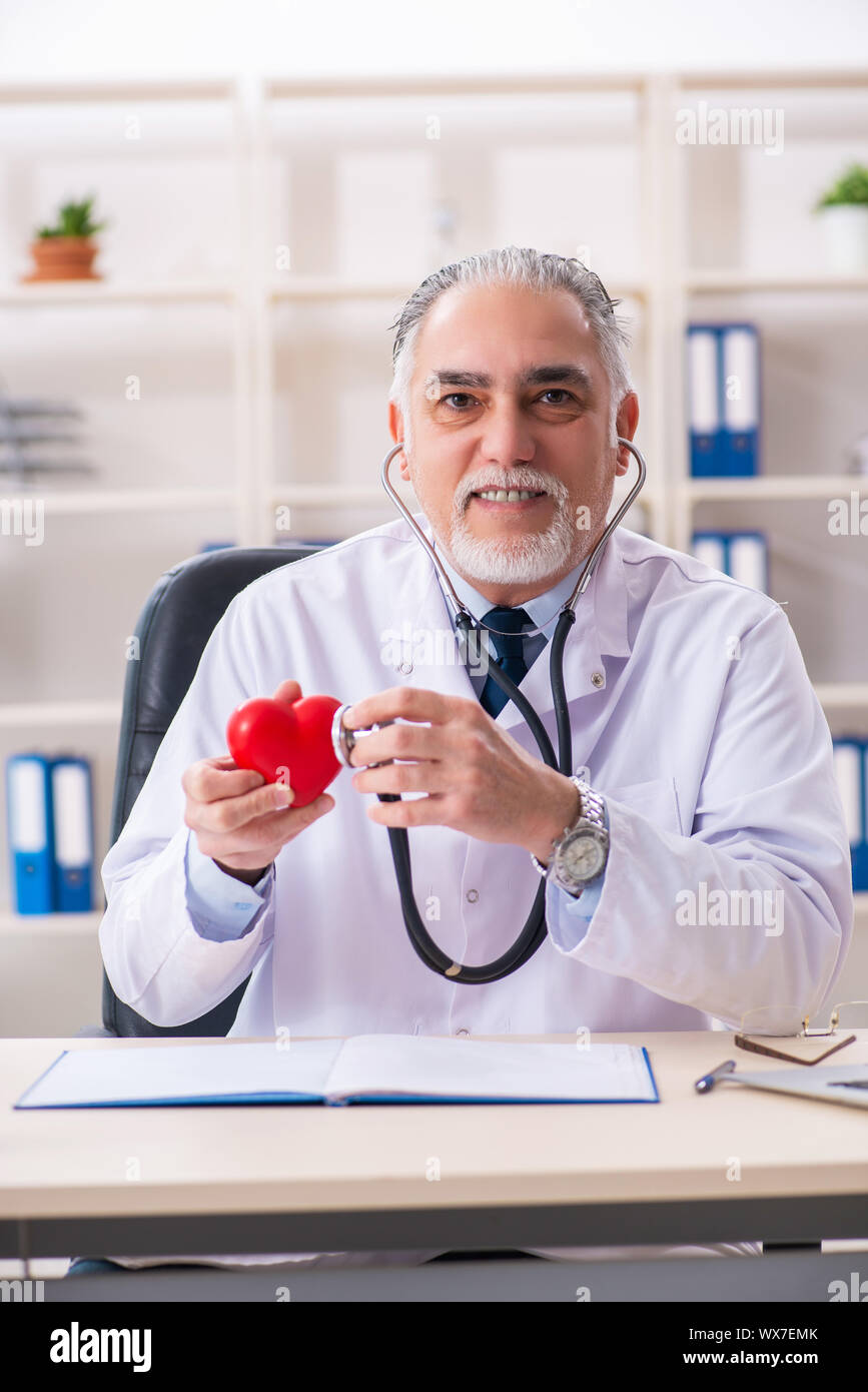 Aged male doctor cardiologist with heart model Stock Photo - Alamy