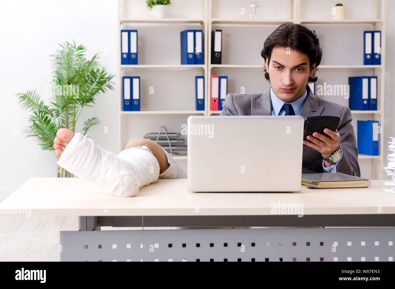 Leg injured employee working in the office Stock Photo - Alamy