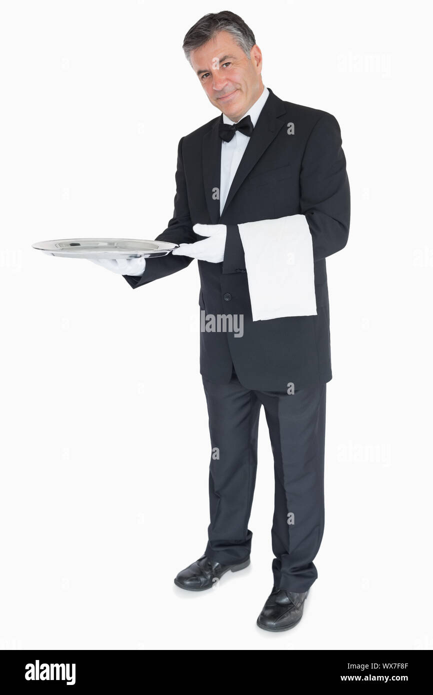 Smiling waiter standing against the white background holding silver ...